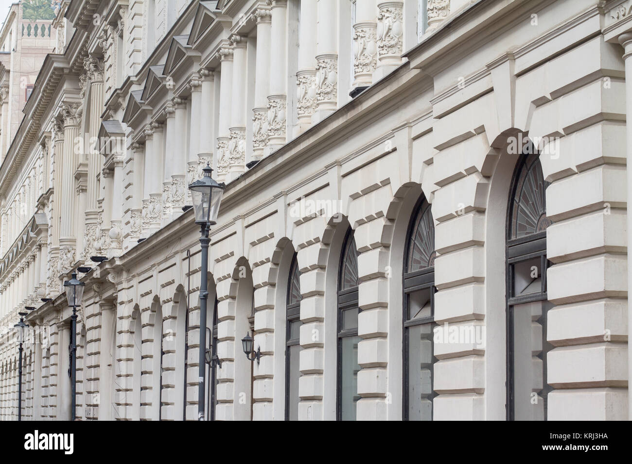 White, classical building architecture with windows and street lights ...