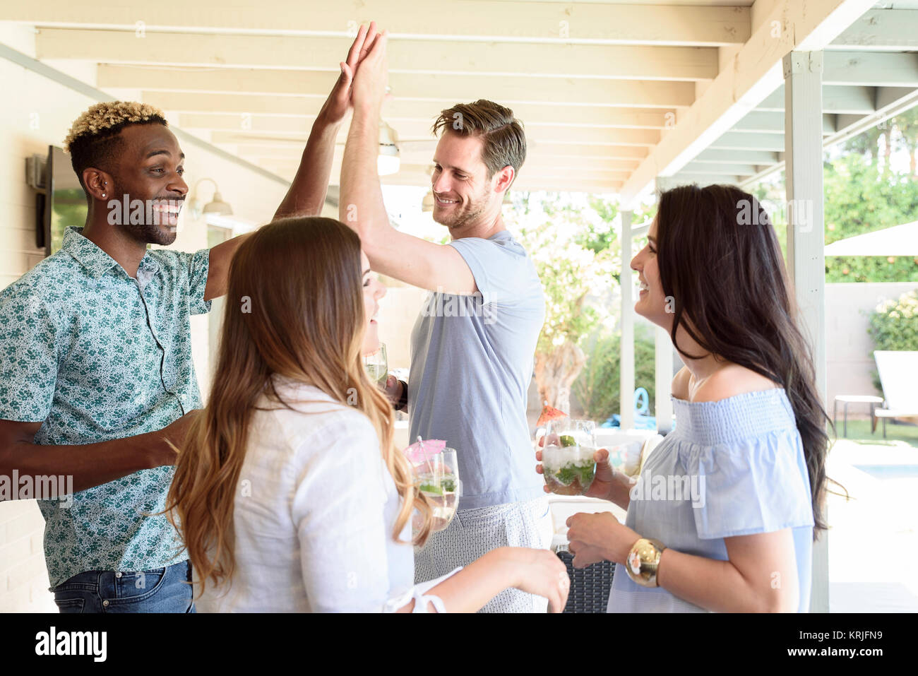 Smiling friends with cold drinks high-fiving outdoors Stock Photo - Alamy
