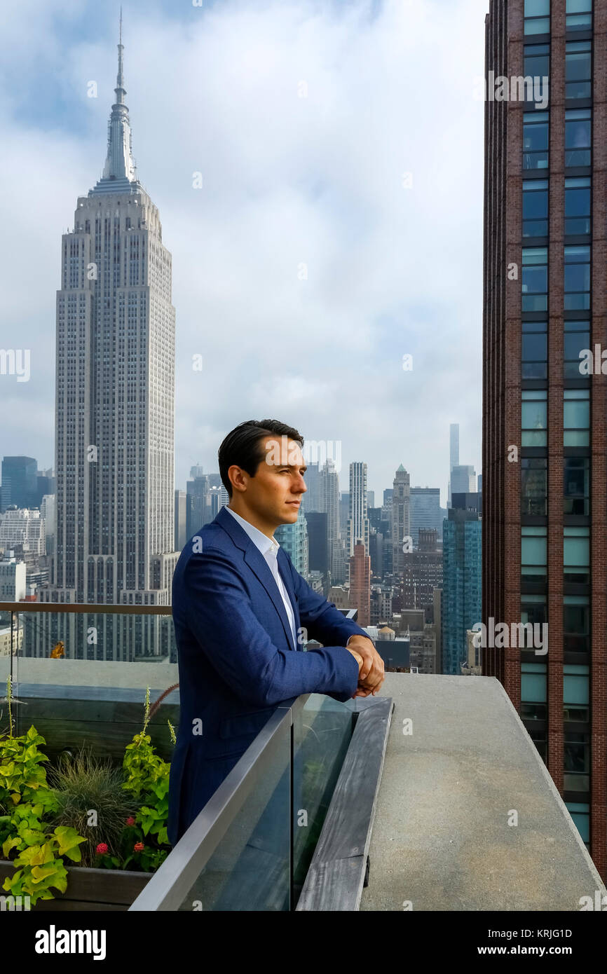 Pensive Caucasian businessman leaning on urban rooftop Stock Photo - Alamy