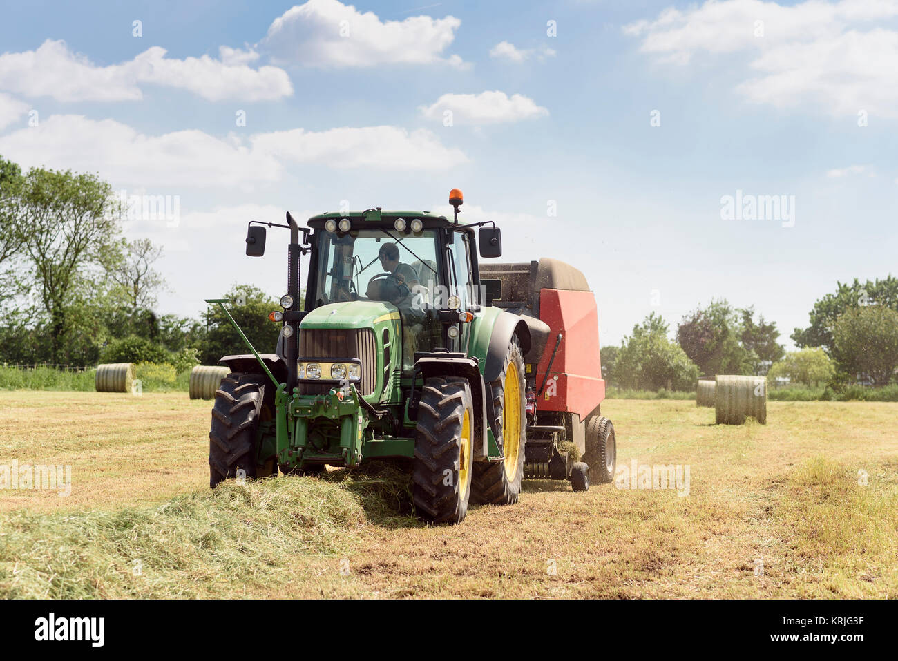 Caucasian man driving tractor baling hay Stock Photo - Alamy