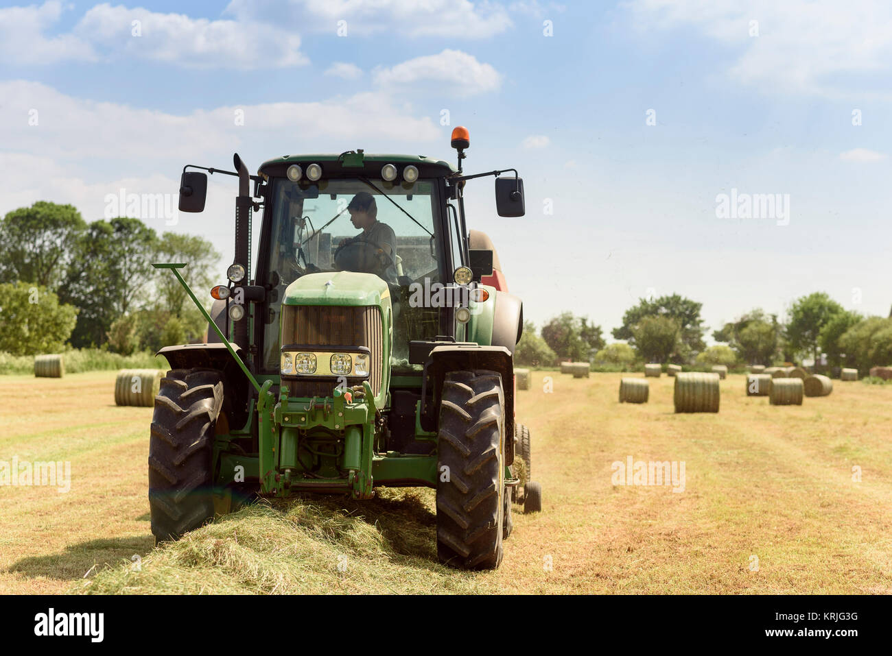 Caucasian man driving tractor baling hay Stock Photo - Alamy