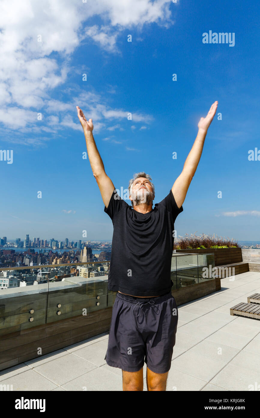 Caucasian man standing with arms raised on urban rooftop Stock Photo ...