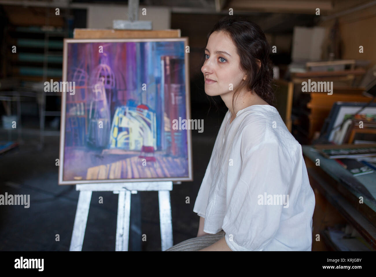 Caucasian artist sitting near paintings Stock Photo - Alamy