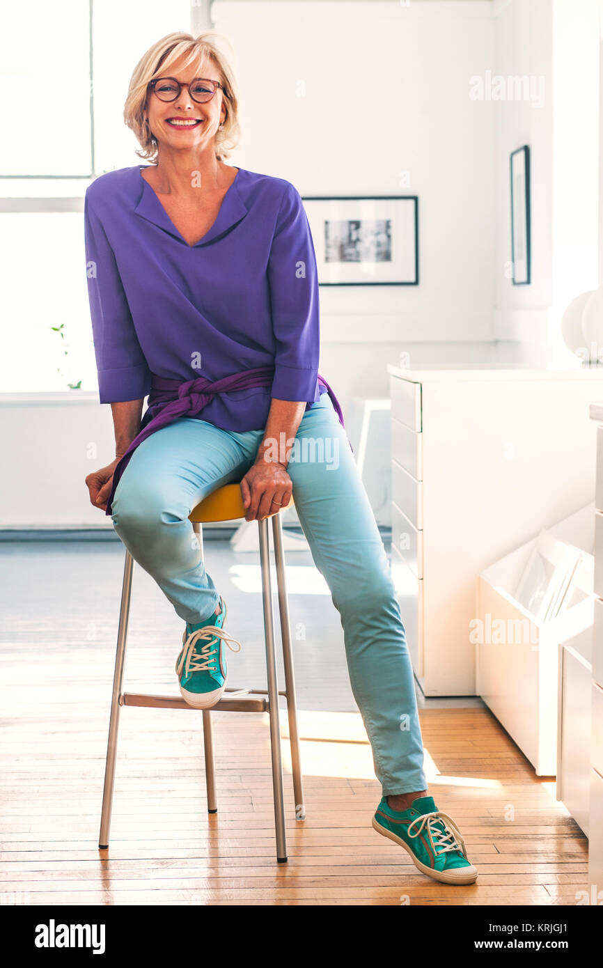 Smiling Caucasian woman sitting on stool Stock Photo - Alamy