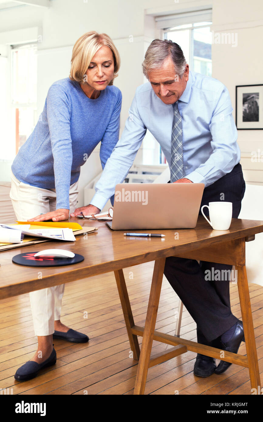 Caucasian business people leaning on table using laptop Stock Photo - Alamy