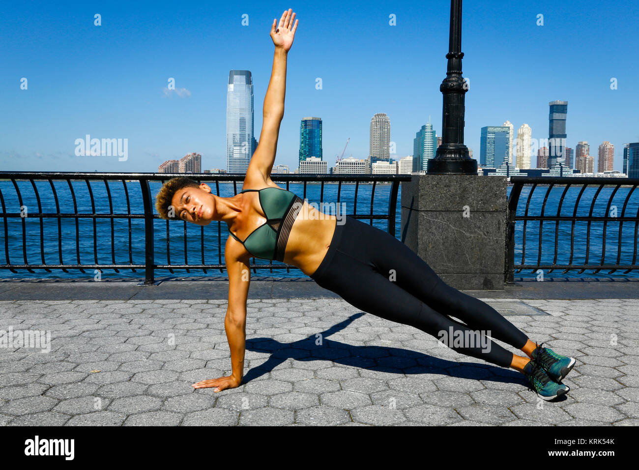 Mixed race woman balancing on arm at waterfront Stock Photo - Alamy