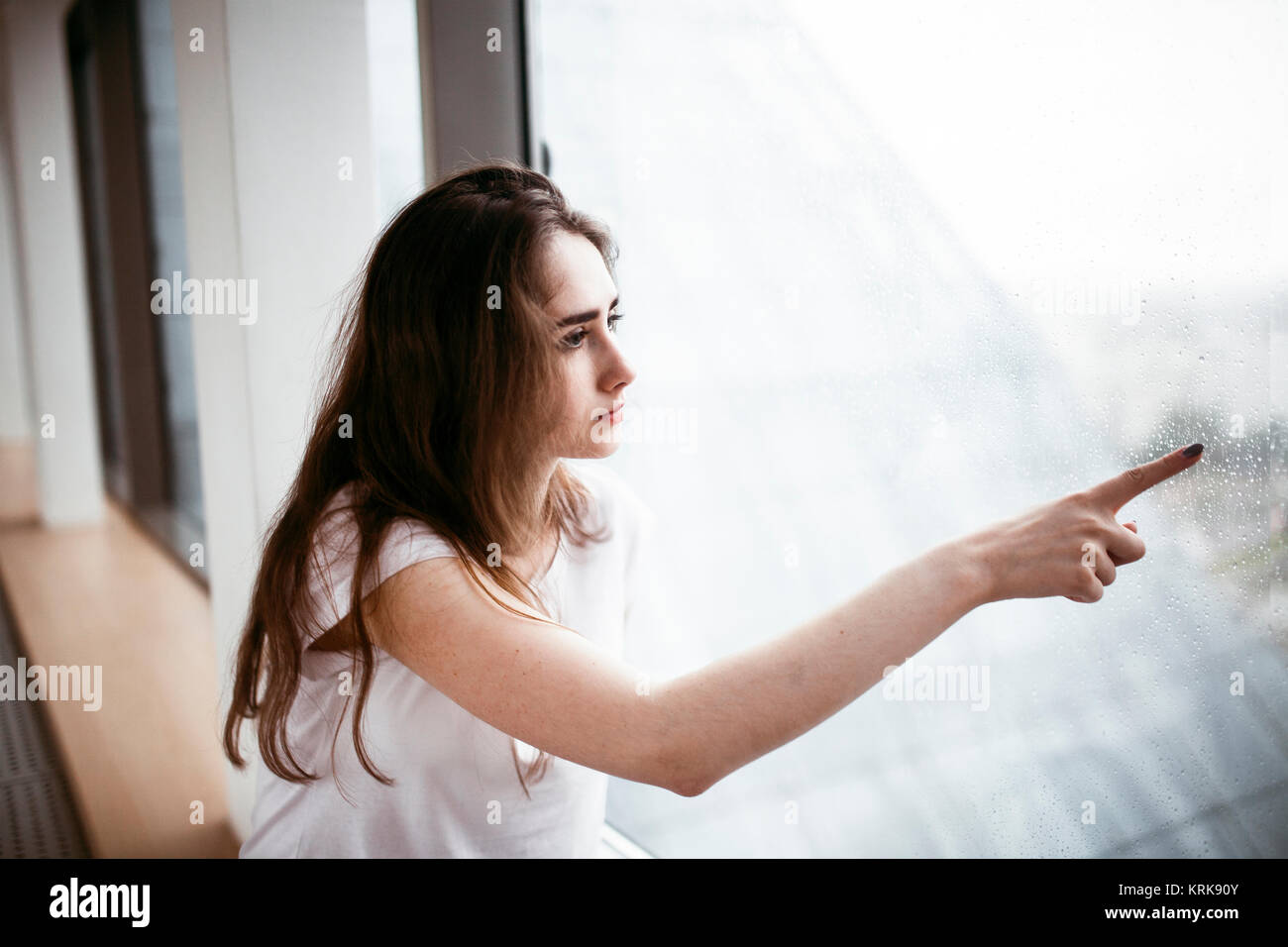 Caucasian woman pointing at rain on window Stock Photo - Alamy