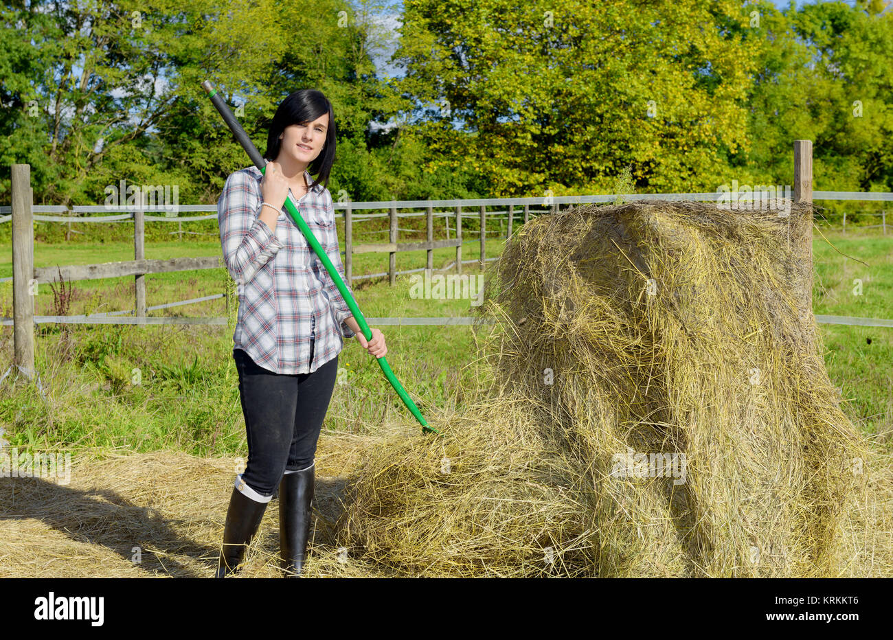 Young pretty country woman working on the farm, loading straw Stock ...