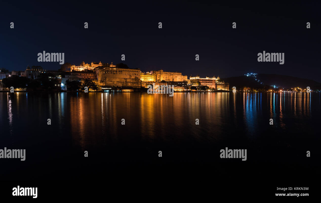 Udaipur cityscape by night. The majestic city palace reflecting lights ...