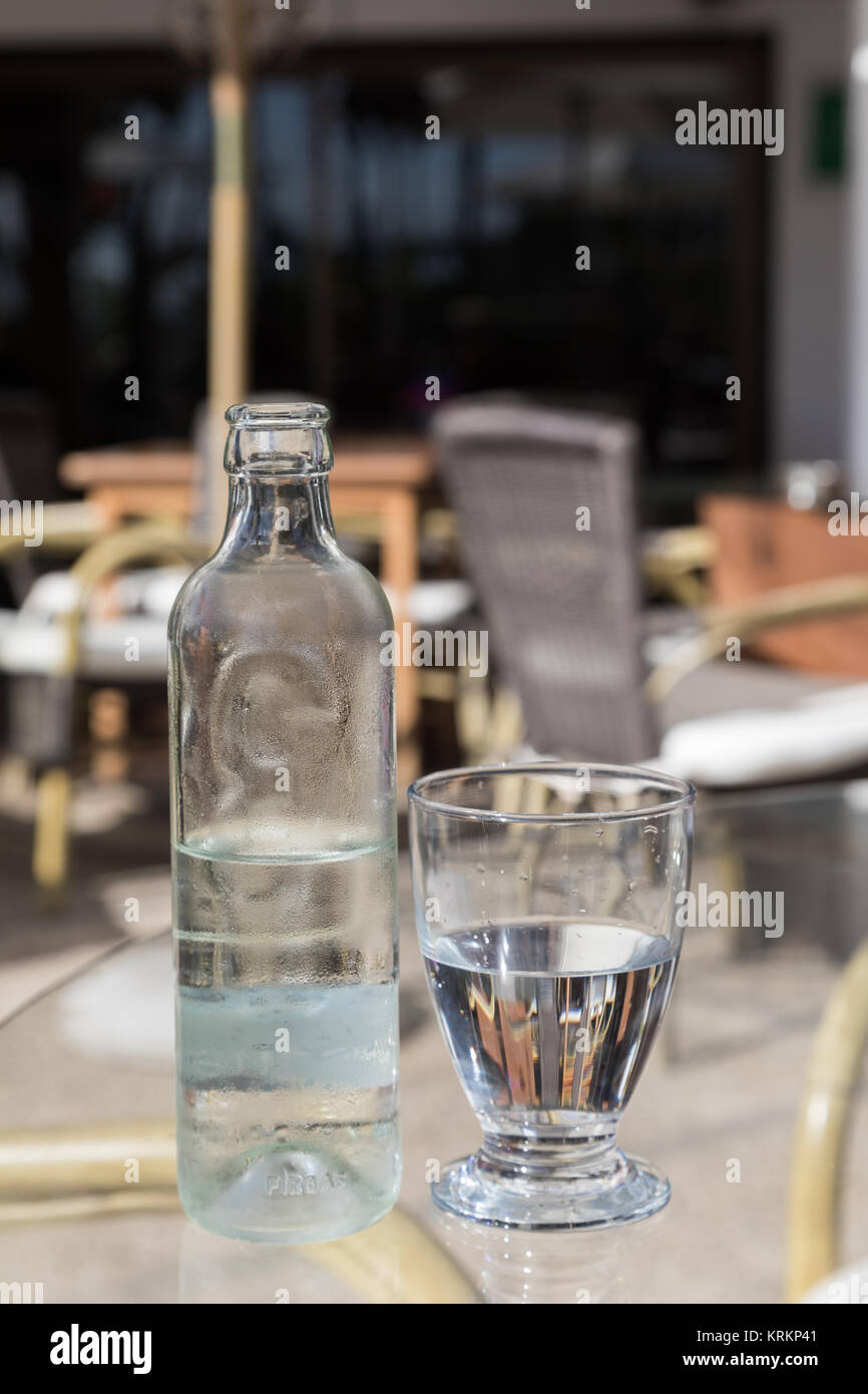 Cold fresh water in glass bottle with glass on a cafe table, vertical ...