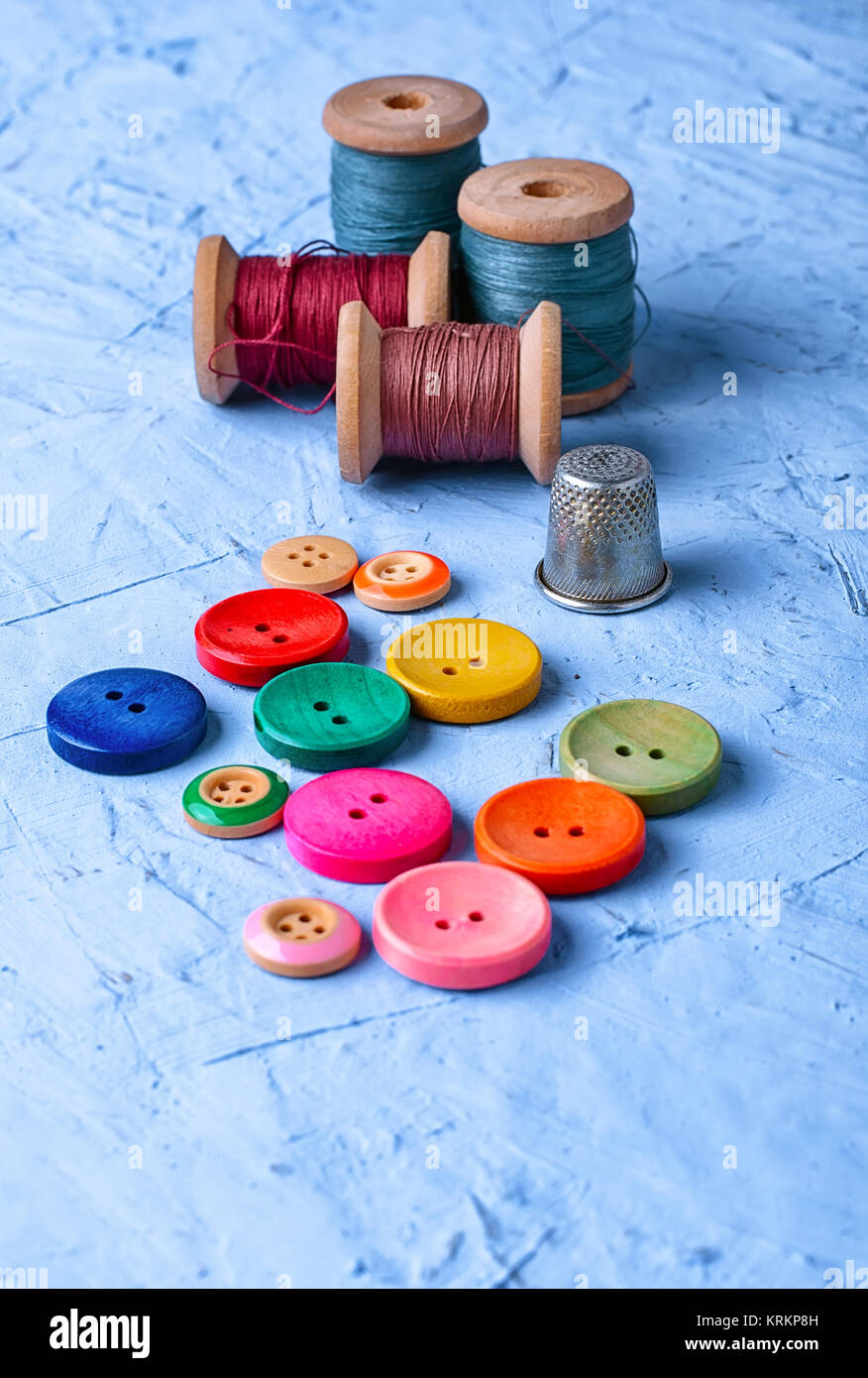 Set of buttons and thread on bright blue background Stock Photo - Alamy