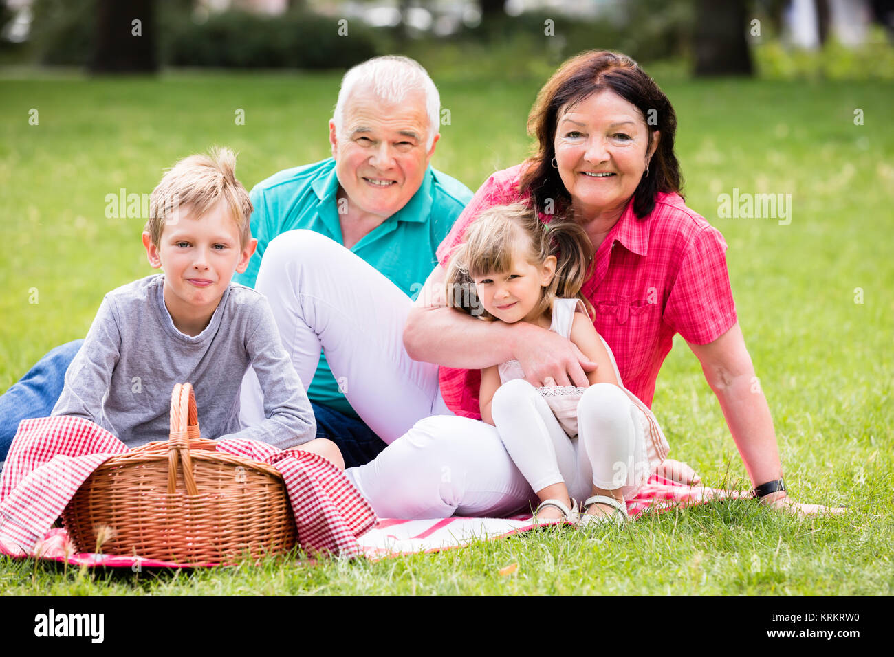 Grandparent And Grandchildren Sitting In Park Stock Photo - Alamy