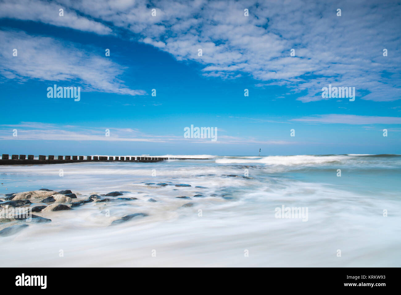 Flowing beach water moving over rocks Stock Photo - Alamy
