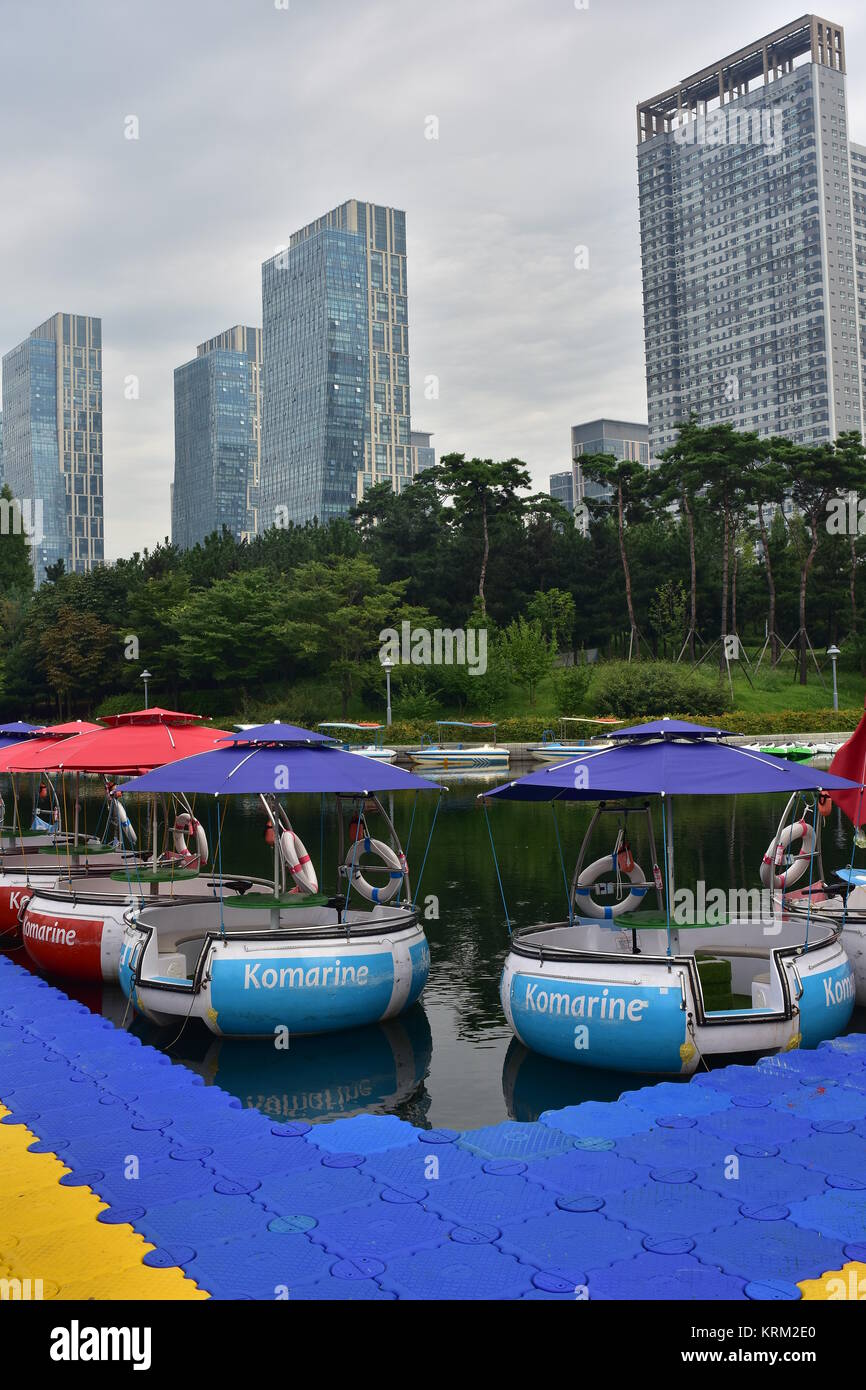 Circular boats in artificial canal with forest park and tall apartment ...