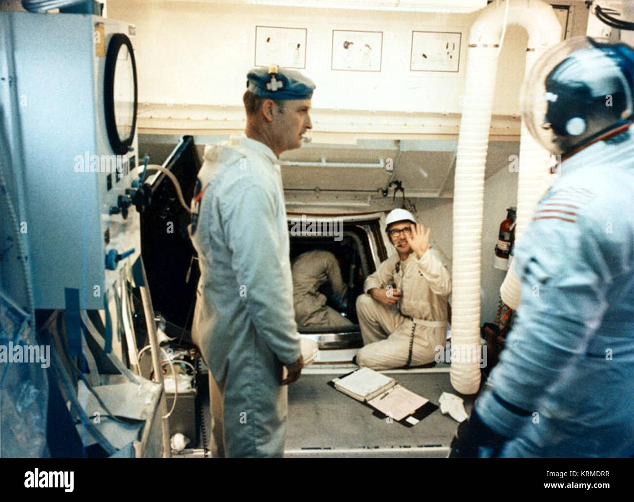 Guenter Wendt seated at the Command Module hatch signals to the crew ...