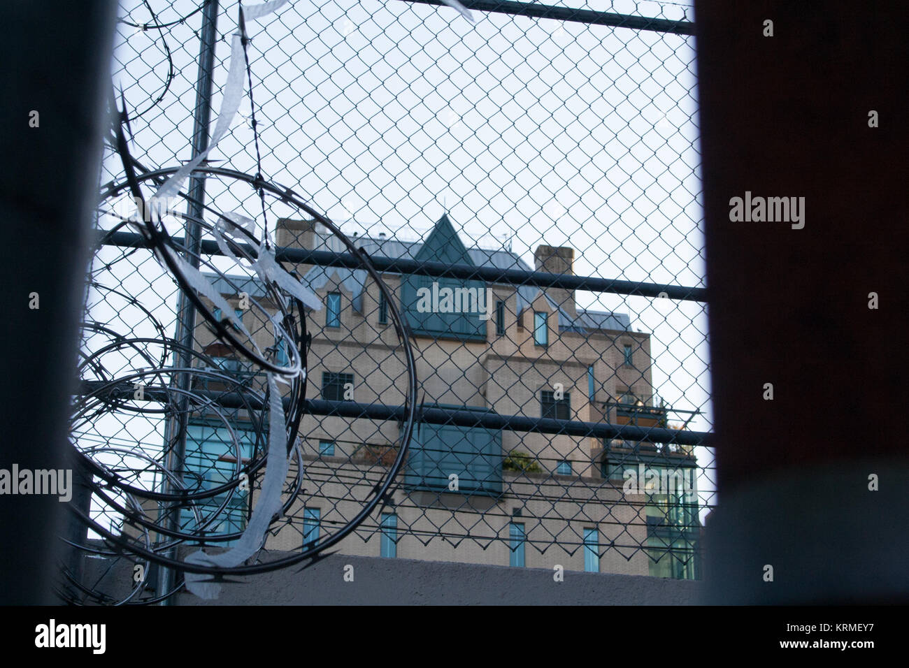 building viewed through fence and barbed wire Stock Photo - Alamy