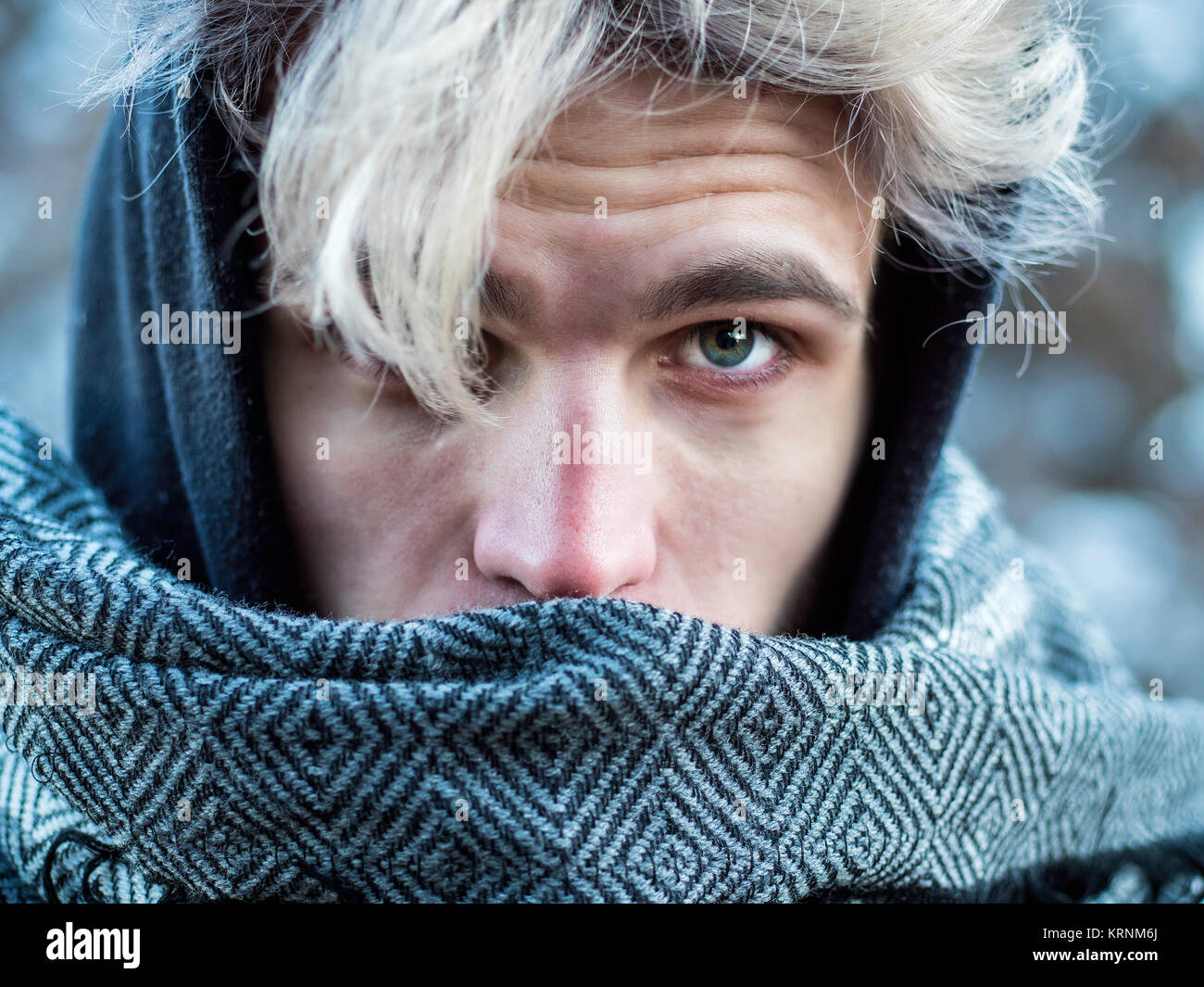 Headshot of young man in hoodie posing outdoor in winter setting with ...