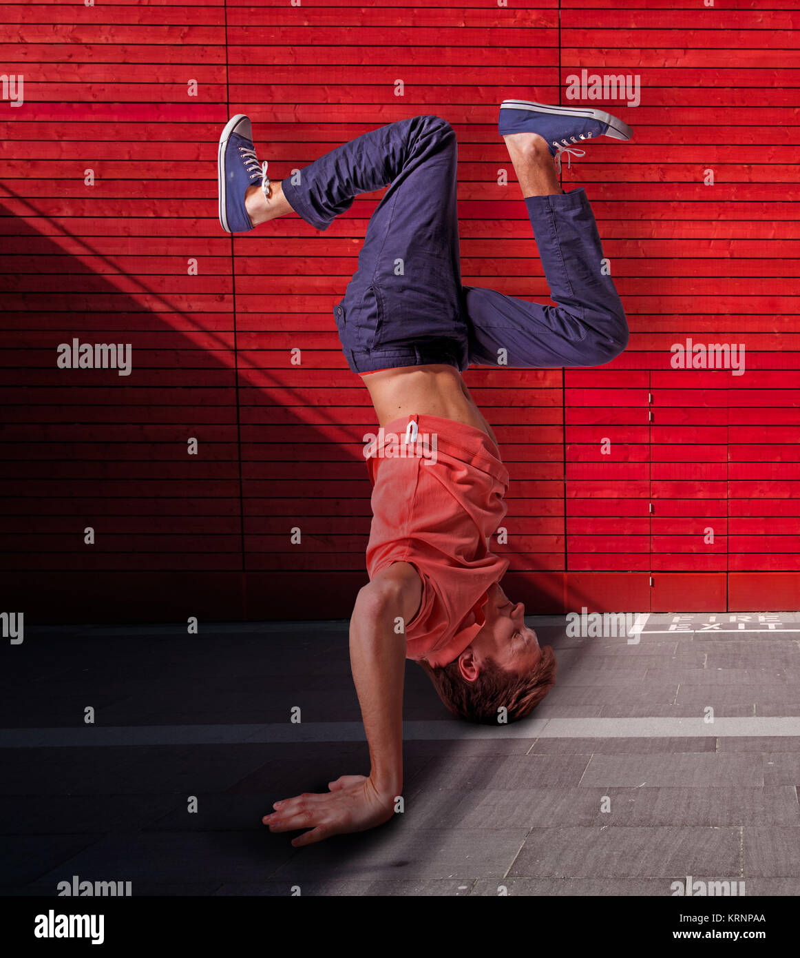 Break dancer doing handstand against red wall background Stock Photo ...