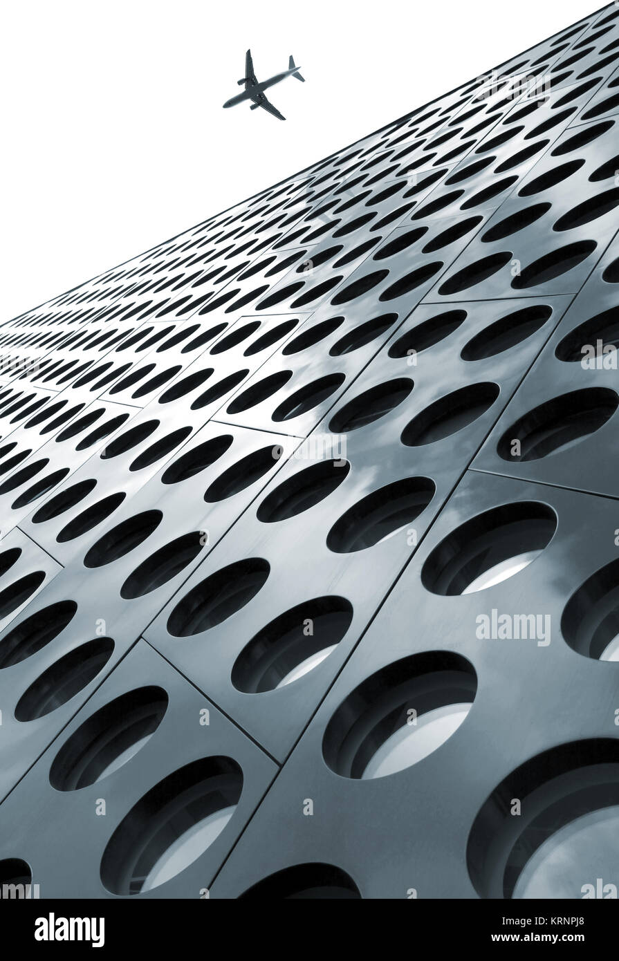 Airplane flying over modern building Stock Photo - Alamy