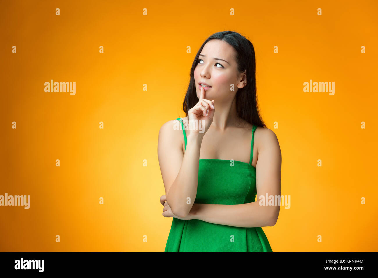 The thinking Chinese girl on yellow background Stock Photo - Alamy