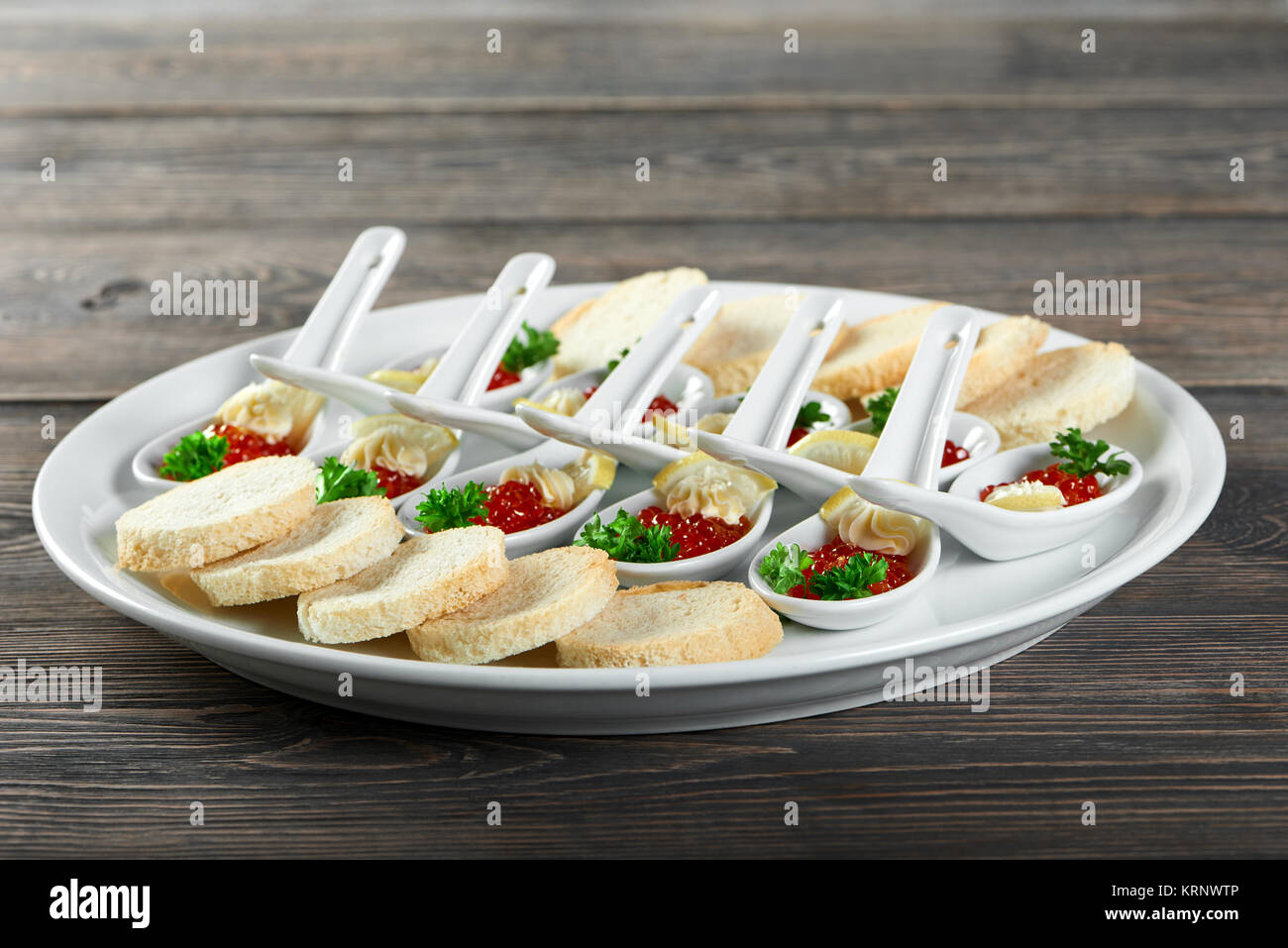 Close-up of a big plate with snacks made from bread,lemons and caviar ...