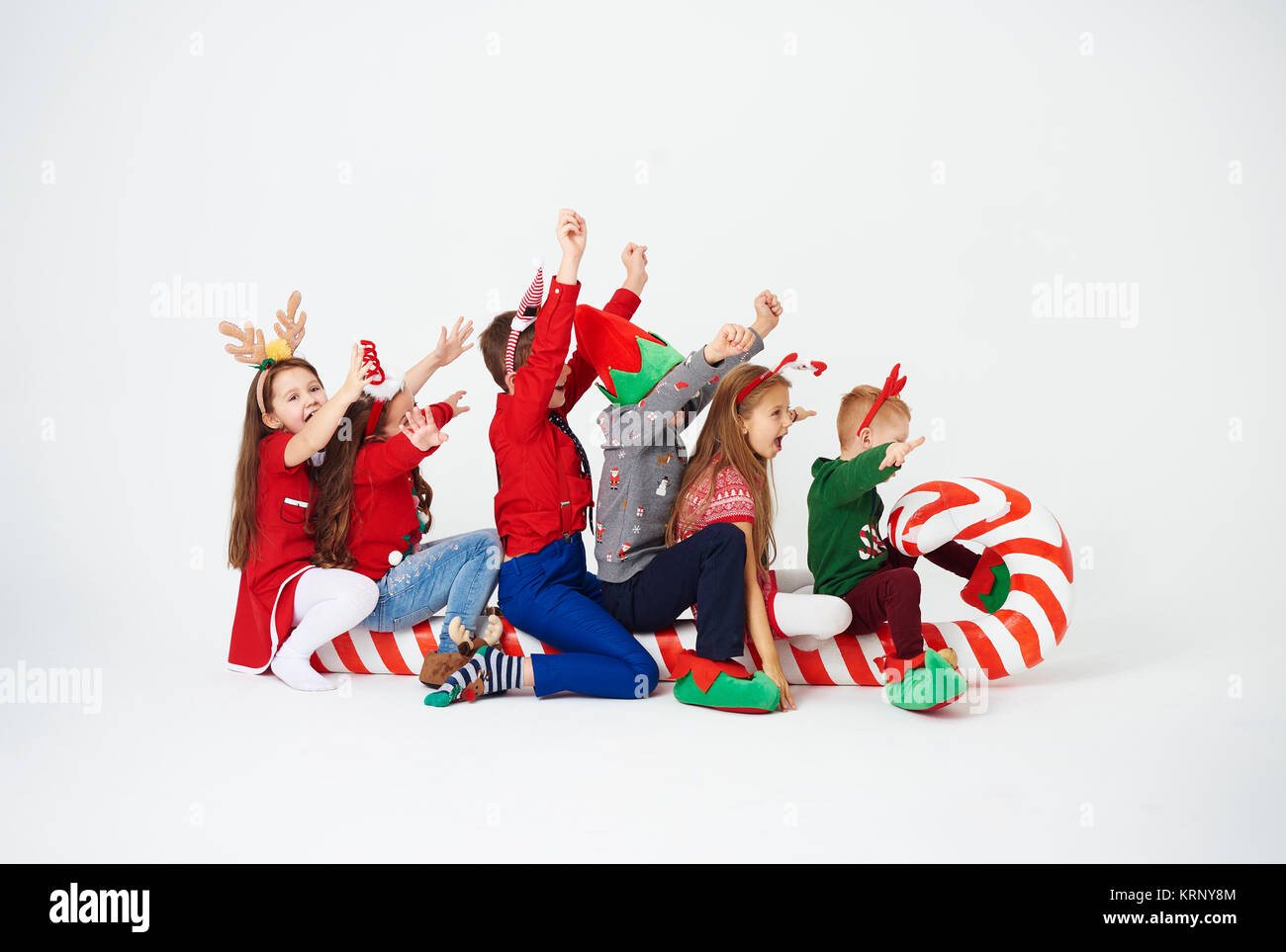 Cheerful children sitting on huge candy cane Stock Photo - Alamy