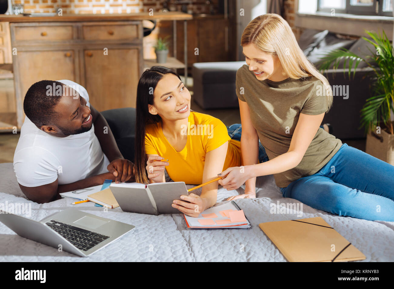 Three reflective happy students talking about task Stock Photo - Alamy