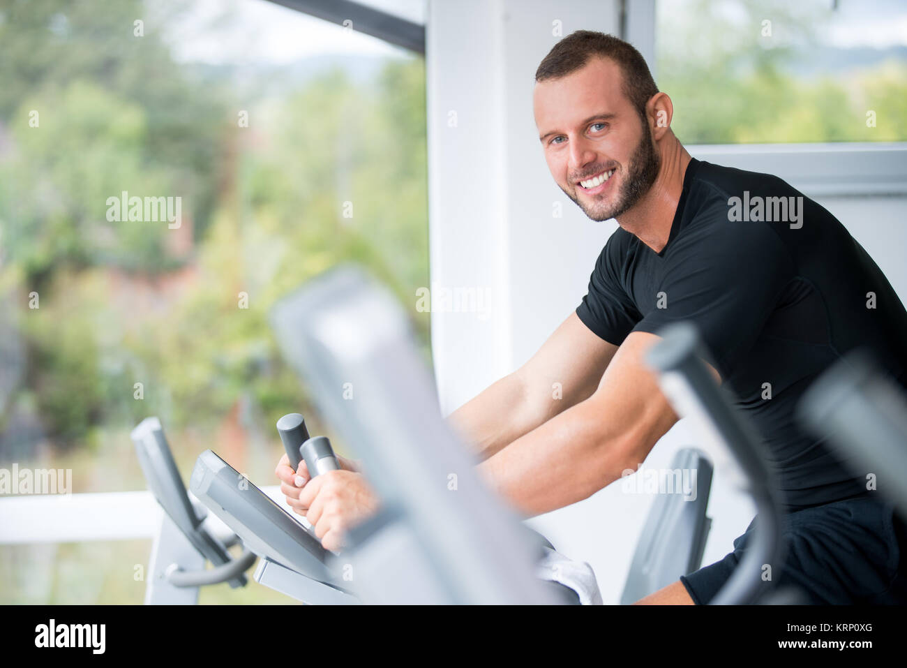 young man exercise bike, cycling, stationary exercising. Indoors gym ...