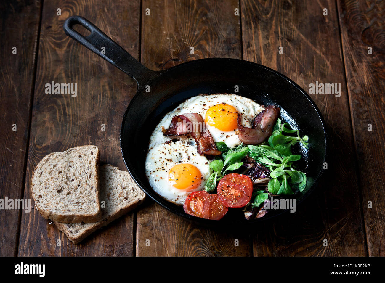 Breakfast set. Pan of fried eggs with bacon, tomato on wooden ...