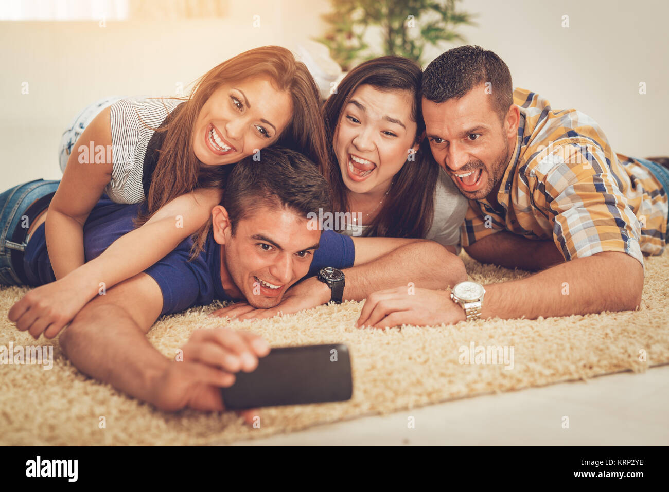Four cheerful best friends having nice time in an apartment and taking ...