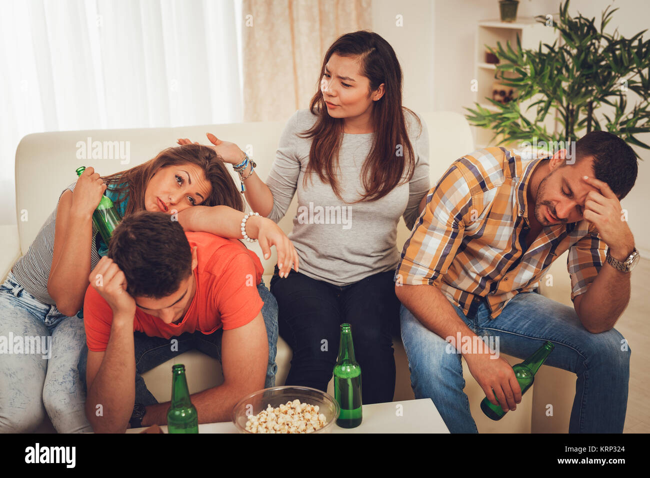 Four young drunk friends sitting on the couch and hangover after house party Stock Photo - Alamy