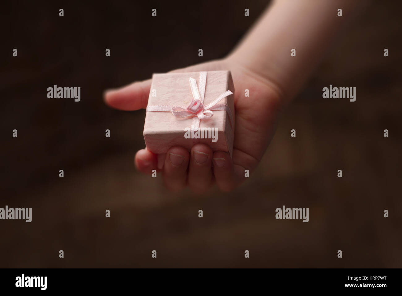 Hand of child holding a small pink gift box Stock Photo - Alamy