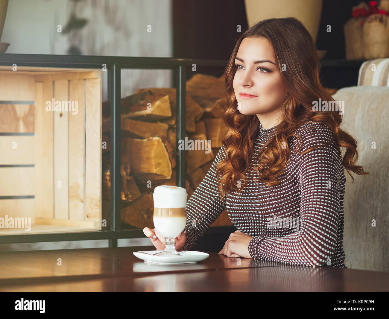 Beautiful young woman sitting in italian style cafe with cup of latte ...