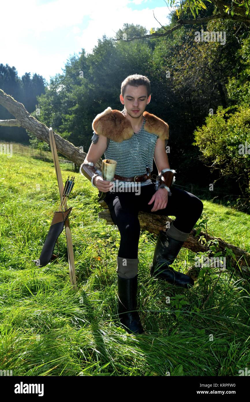 young medieval archer with chain mail sitting on branch,drinking horn ...