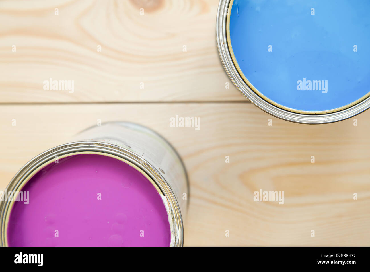 Painting a house. Tin cans of blue and fuchsia oil paint on a light ...