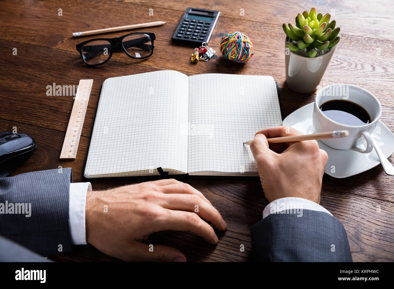 Businessperson Hand Holding Pencil On Notebook Stock Photo - Alamy