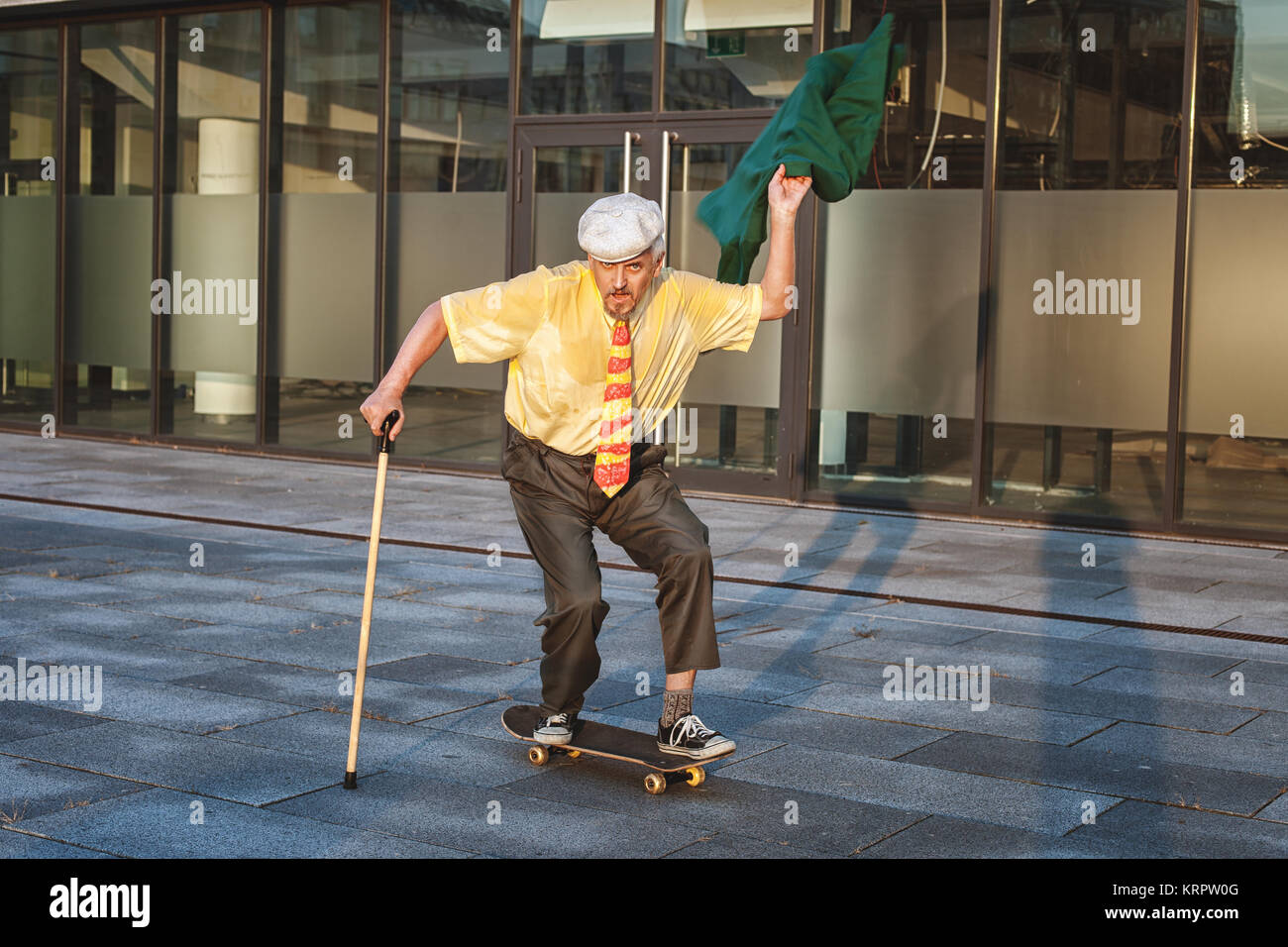Old man is riding on a skateboard, in his hand a walking stick Stock ...