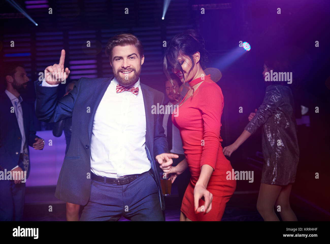 Playful man dancing among people at night club Stock Photo - Alamy
