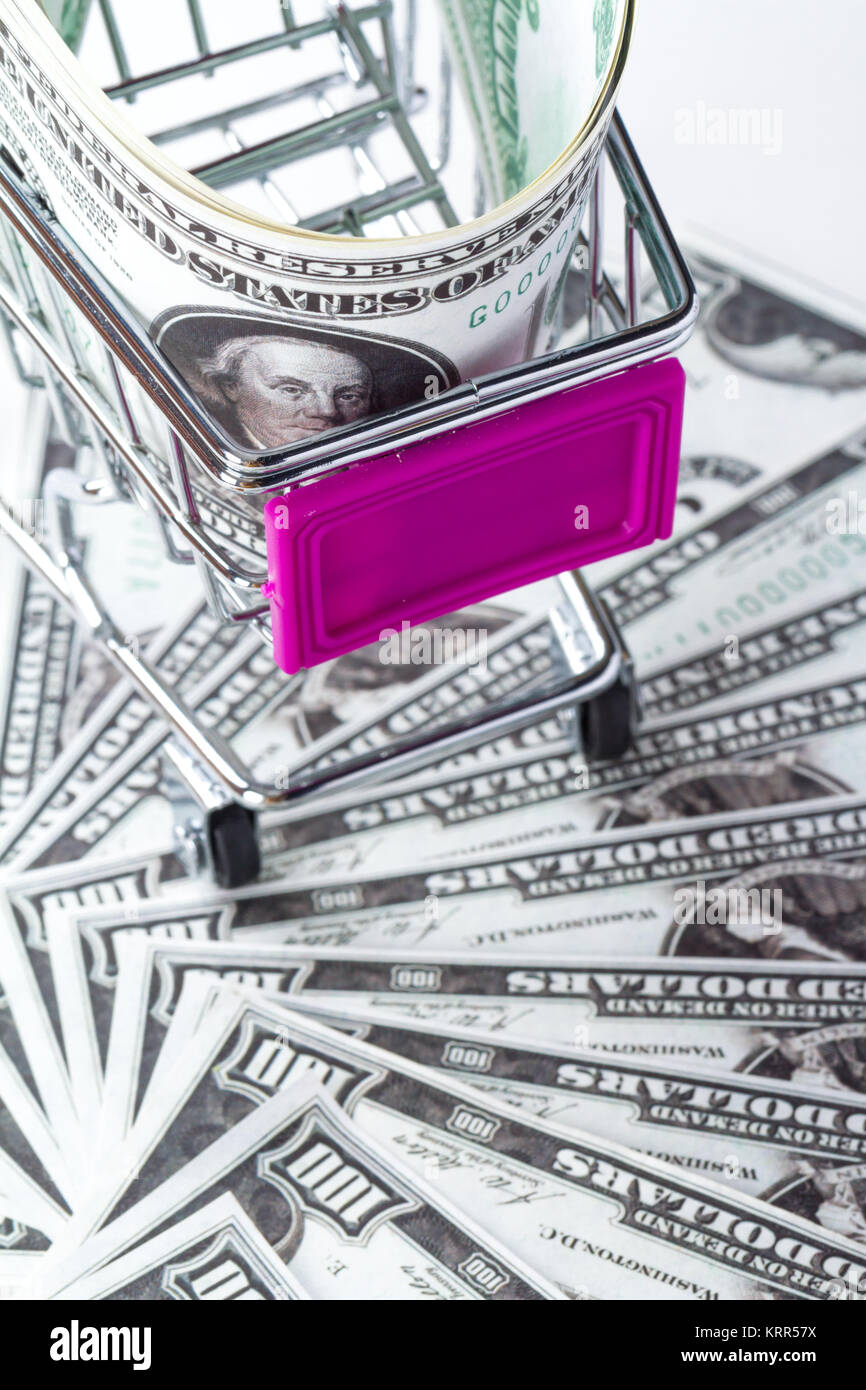 Stack of Dollar banknotes with shopping cart in money consuming concept ...