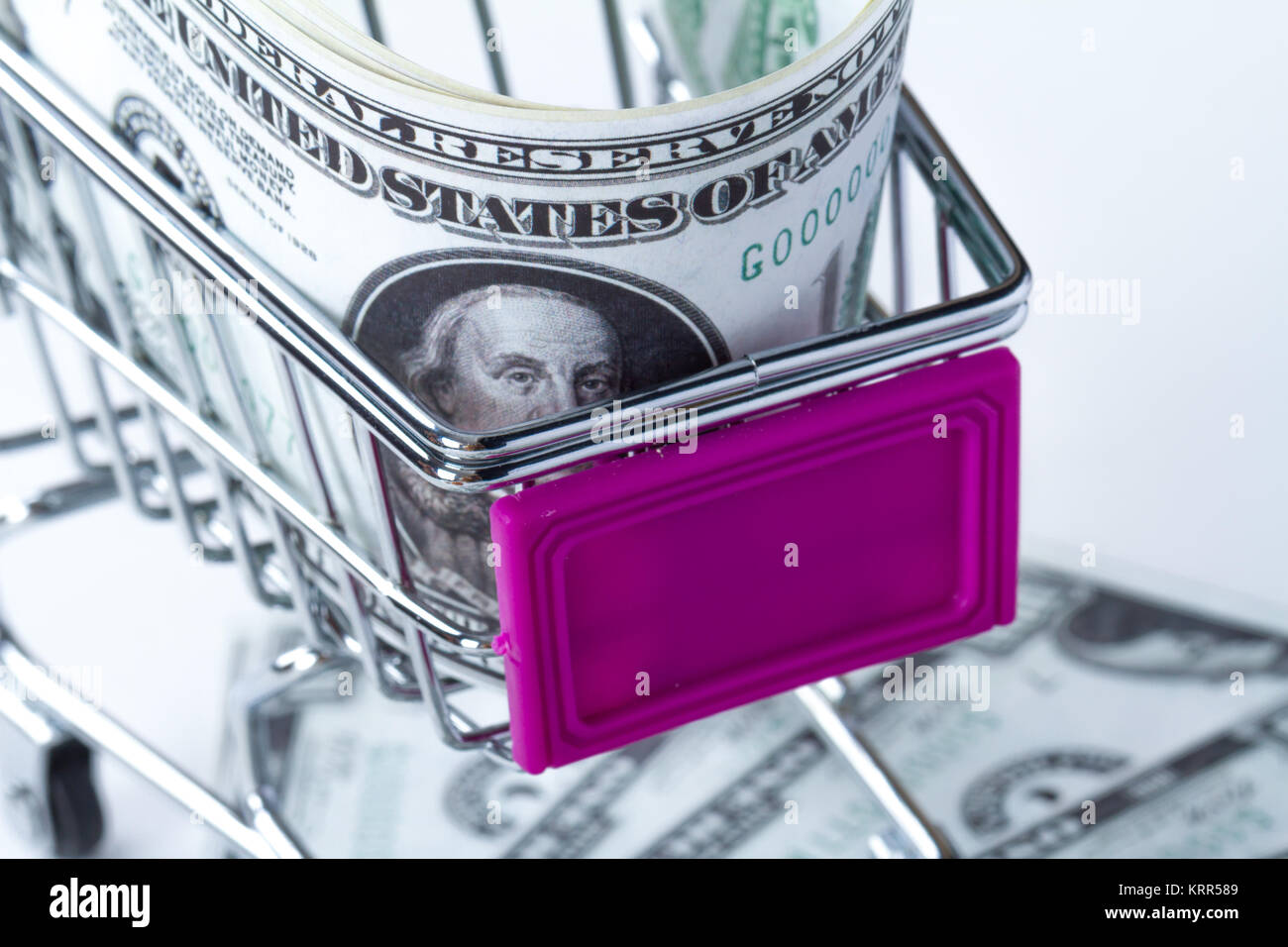 Stack of Dollar banknotes with shopping cart in money consuming concept ...