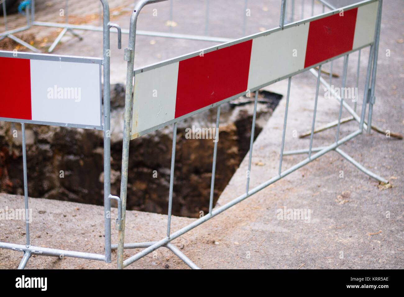 Metal fence barring access to hole in concrete pavement with a hole ...