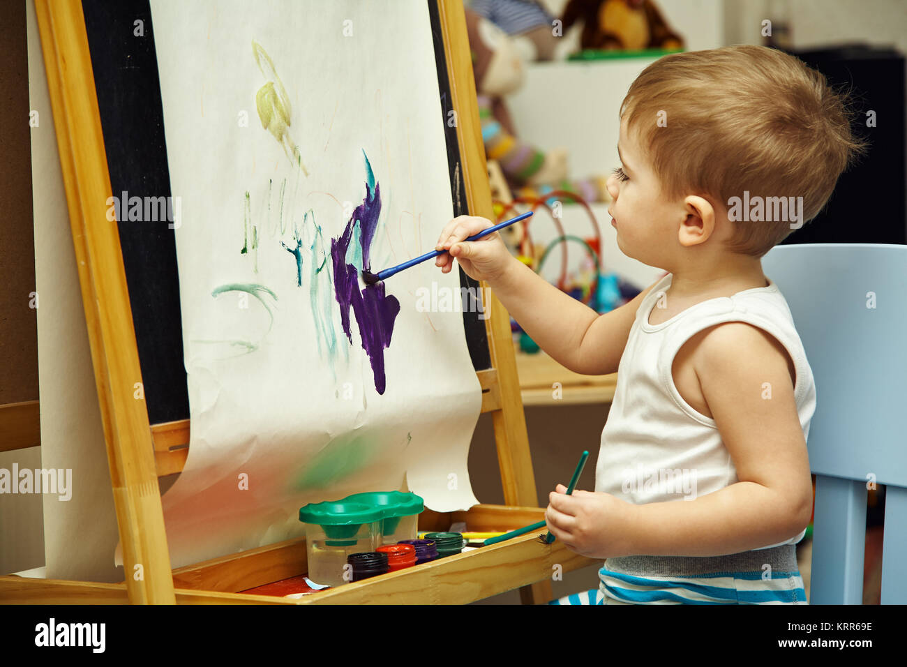 little boy paints a on an easel with a brush. painting child Stock ...