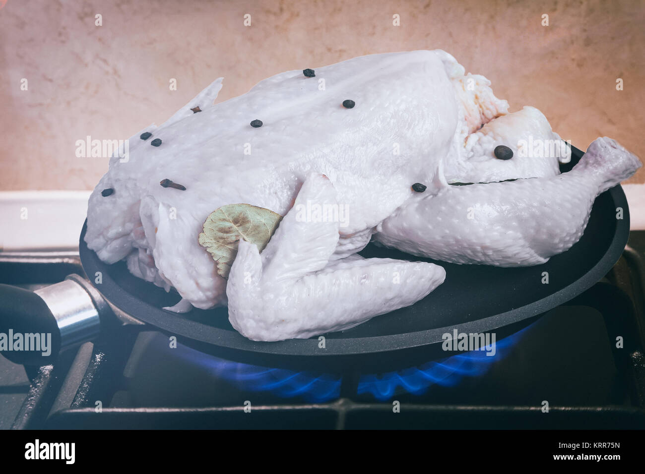 On fire gas stove a frying pan with the chicken prepared for roasting ...