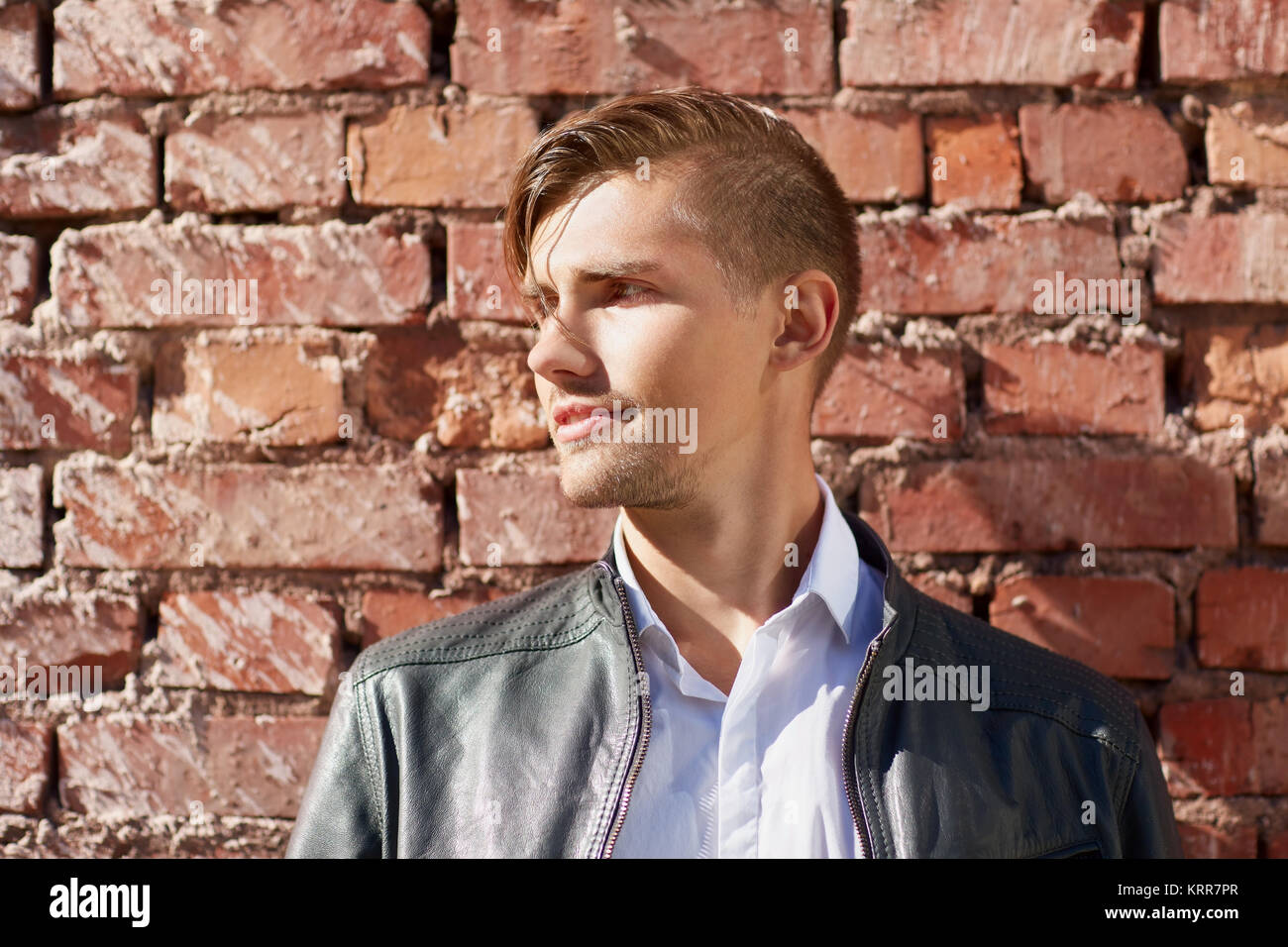 portrait of man in leather jacket over brick wall Stock Photo - Alamy