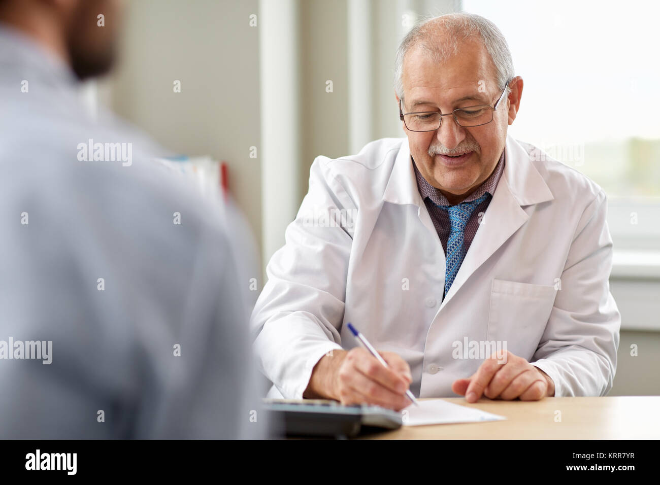 doctor writing prescription for patient at clinic Stock Photo - Alamy