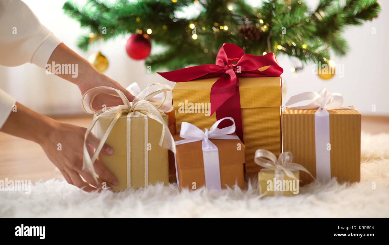 hands putting gift boxes under christmas tree Stock Photo - Alamy