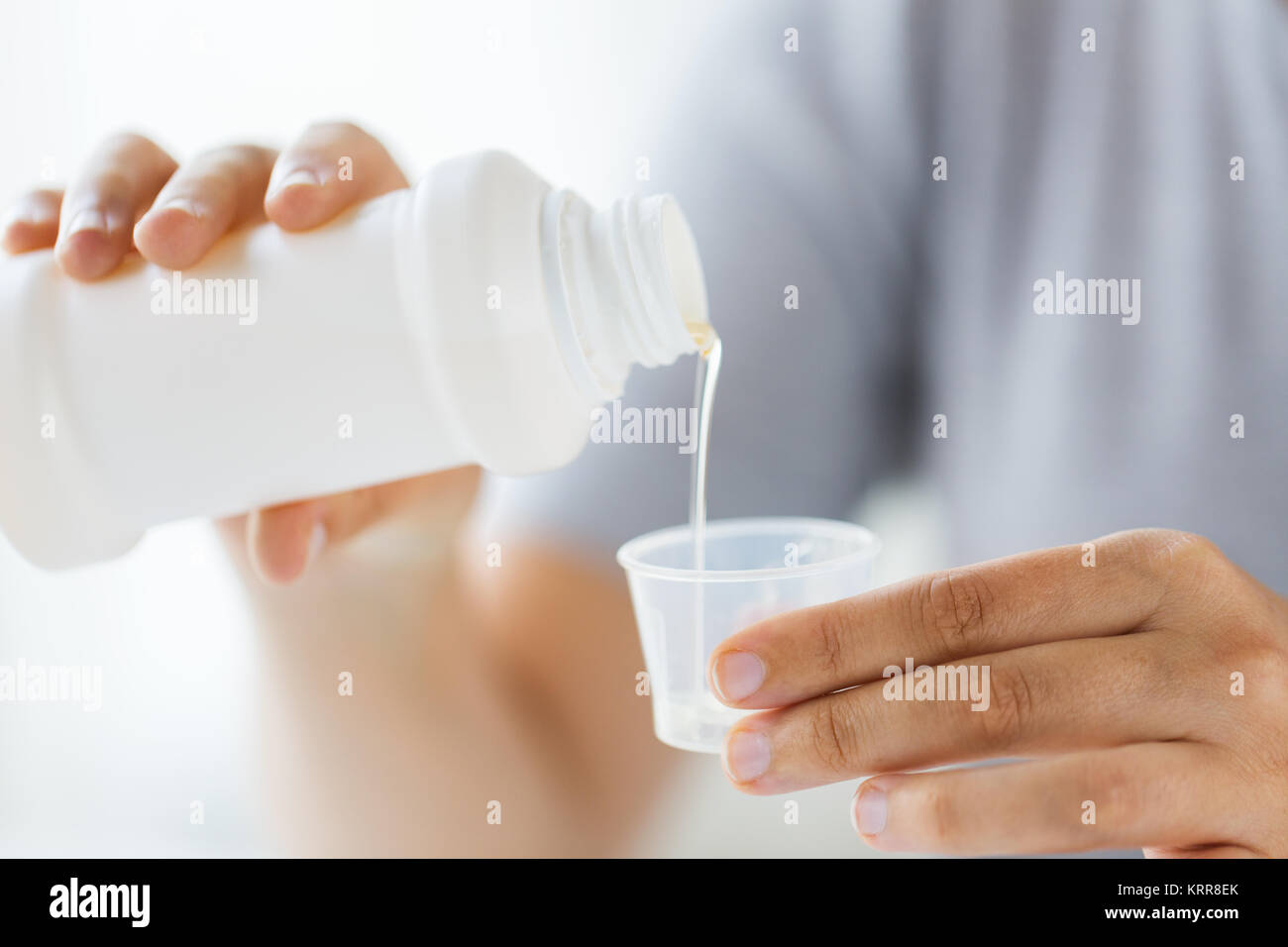woman pouring syrup from bottle to medicine cup Stock Photo - Alamy