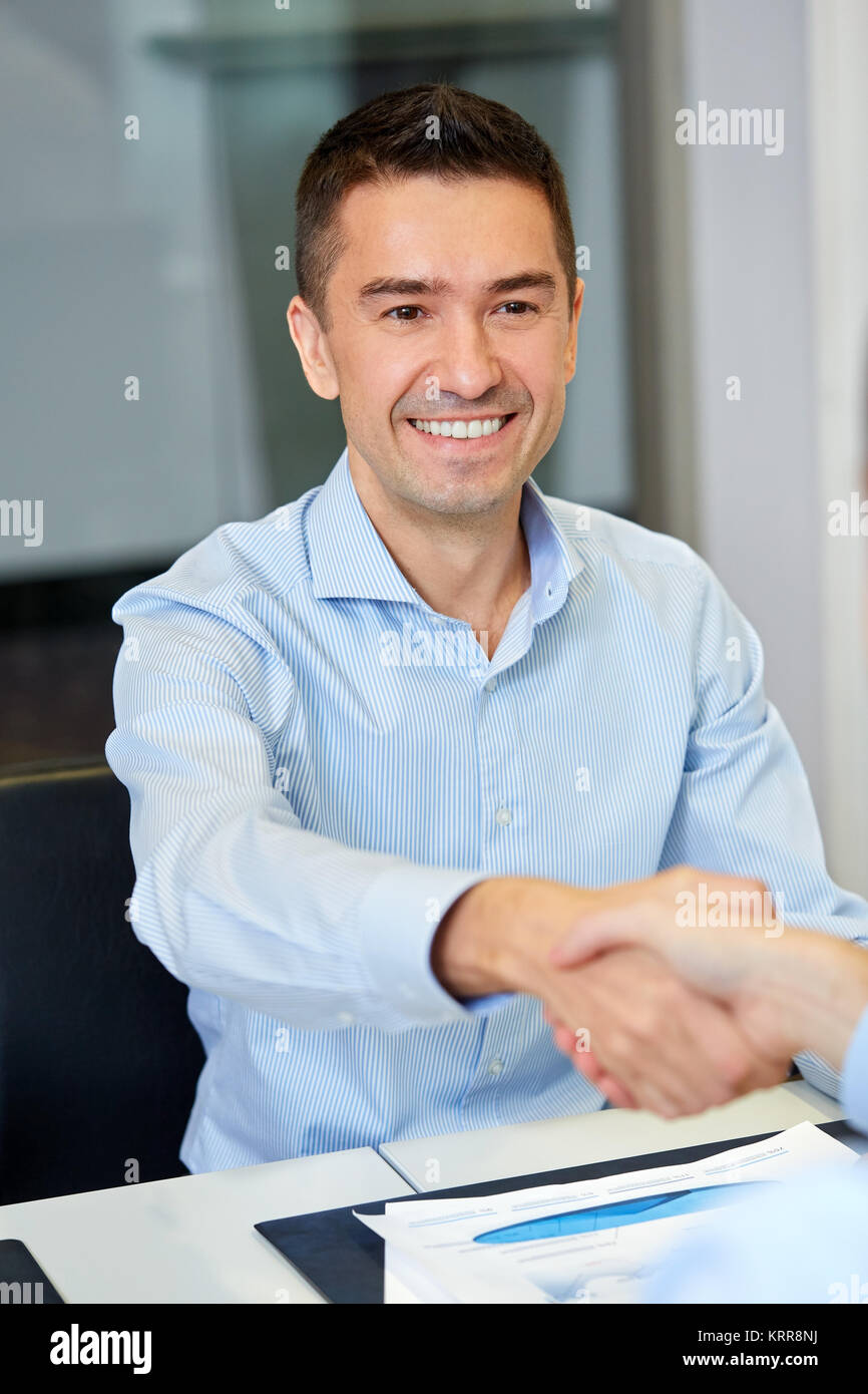 smiling businessman making handshake at office Stock Photo - Alamy