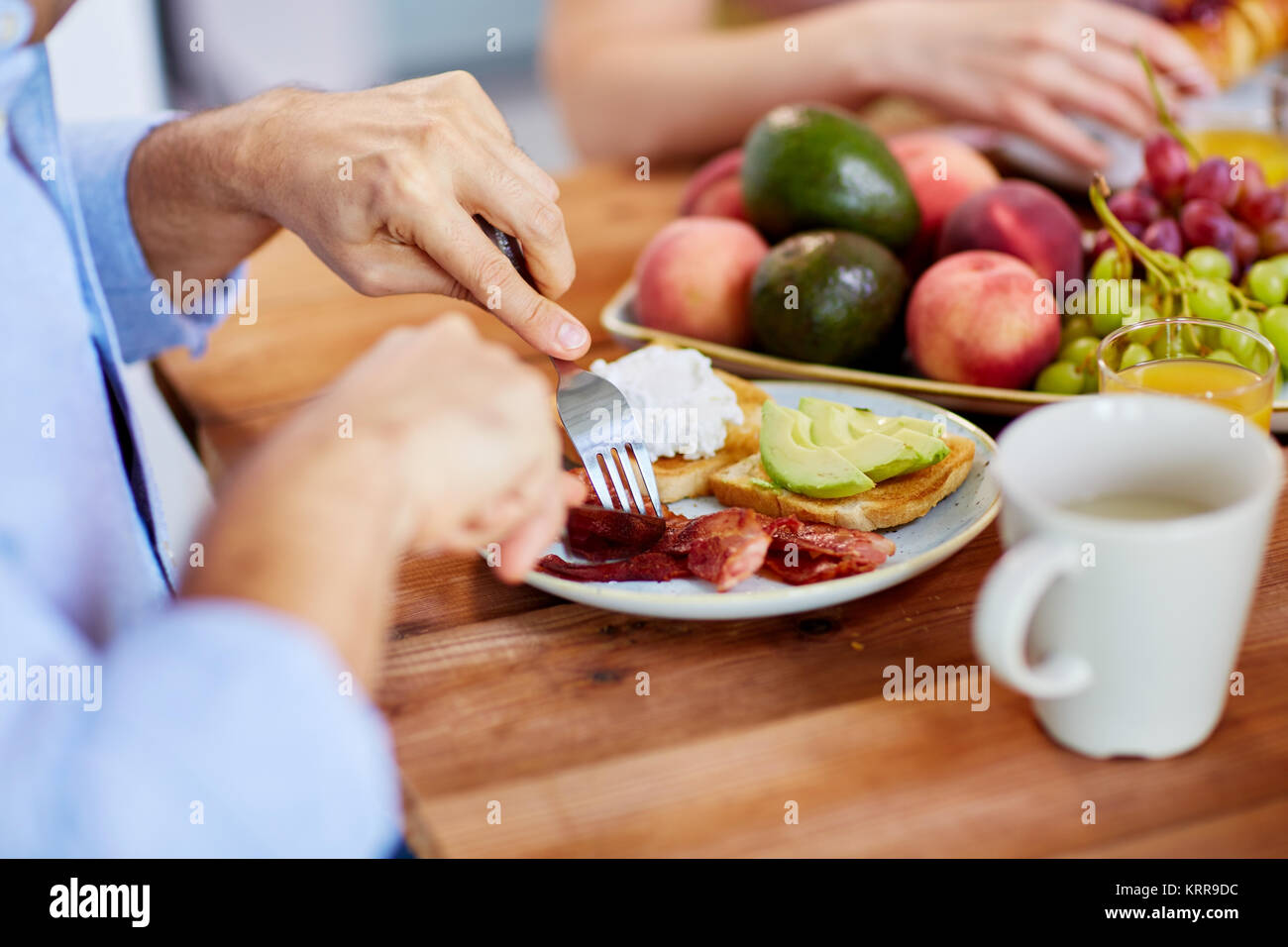 man with fork eating bacon at table full of food Stock Photo - Alamy
