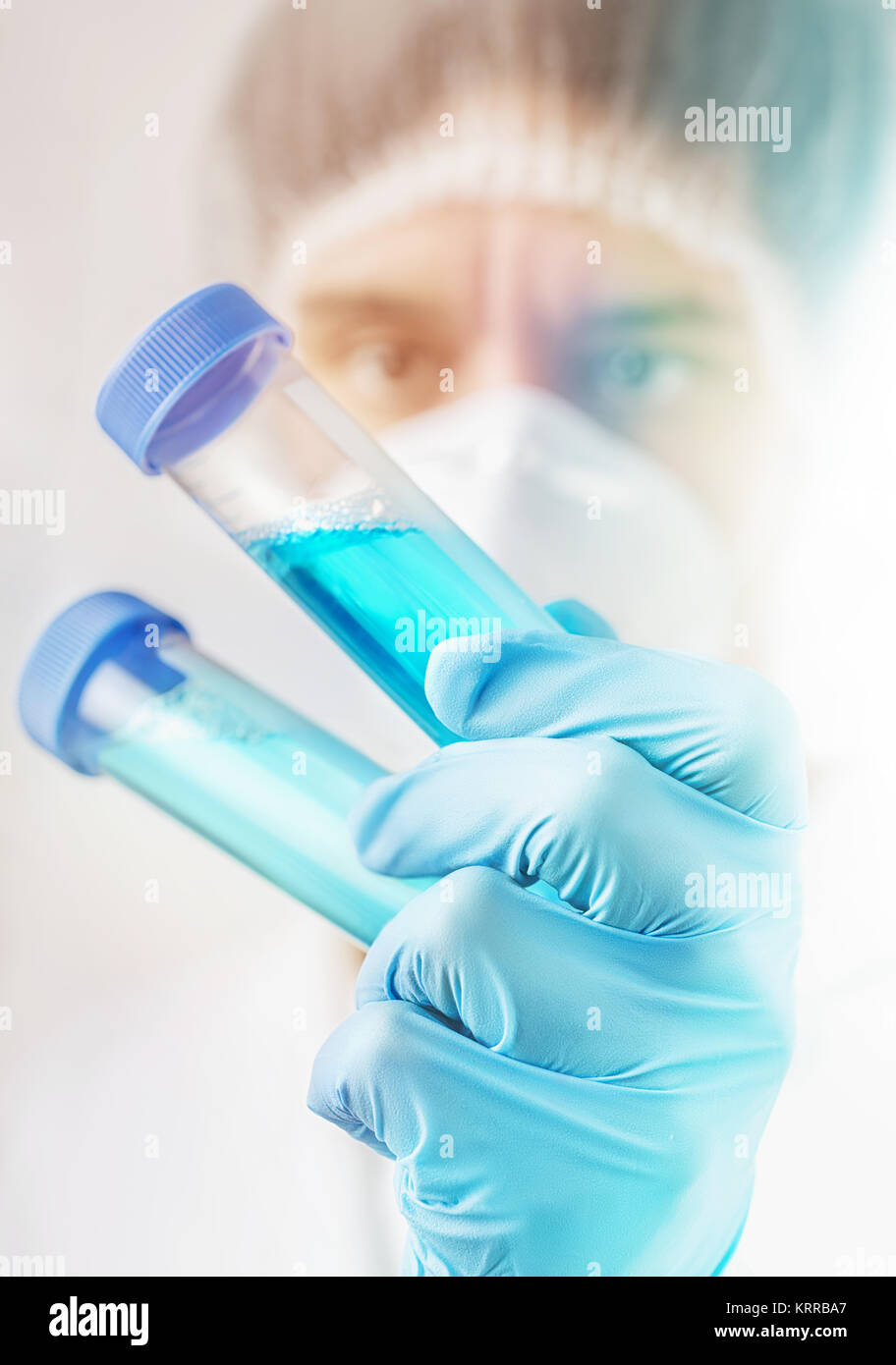 Young male medic or researcher holds up medical samples in gloved hand ...
